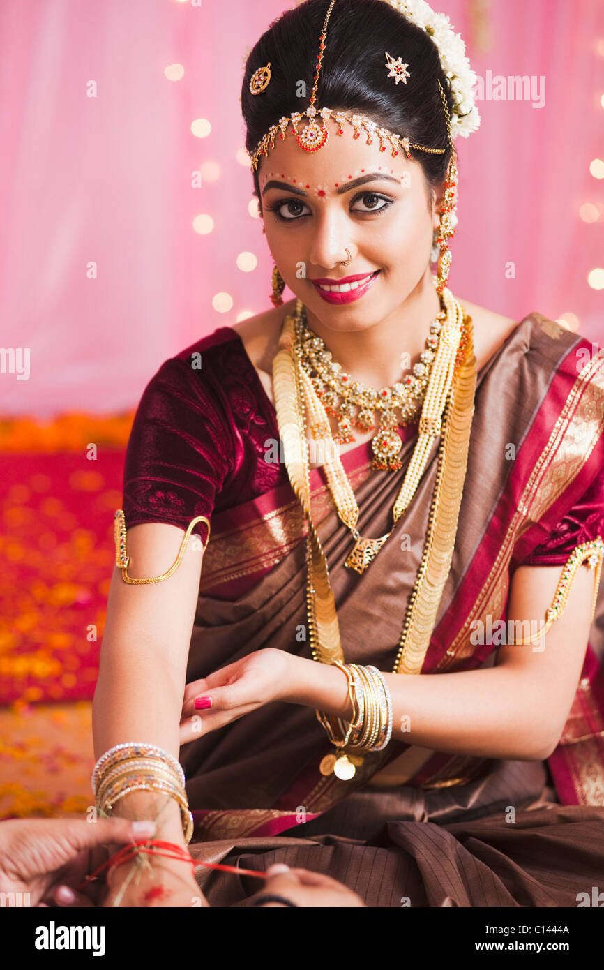Close-up of a person's hands putting holy thread on a bride's wrist ...