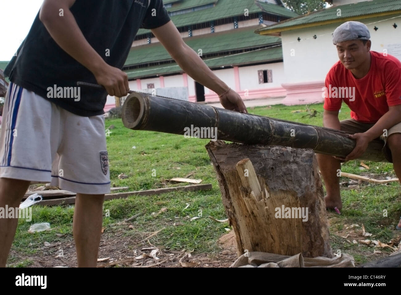 Two men are making a rocket for a festival with wood and bamboo in ...