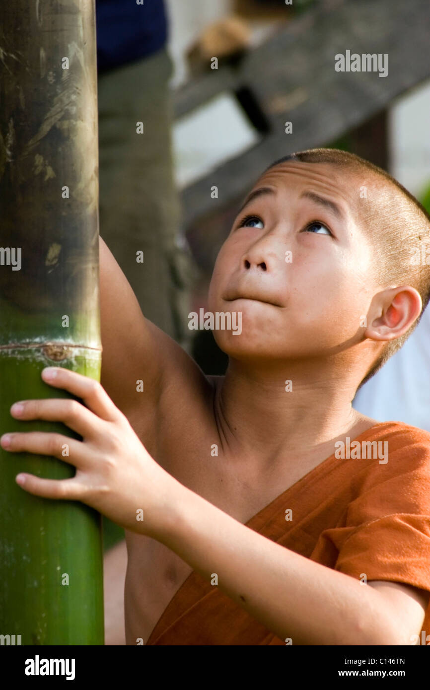 A young Buddhist monk is making a bamboo rocket for a festival at a ...