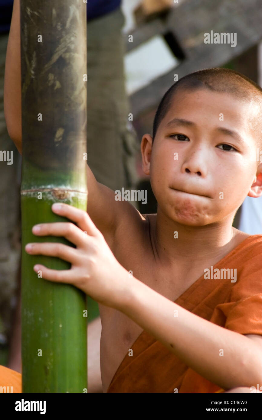 A young Buddhist monk is making a bamboo rocket for a festival at a ...