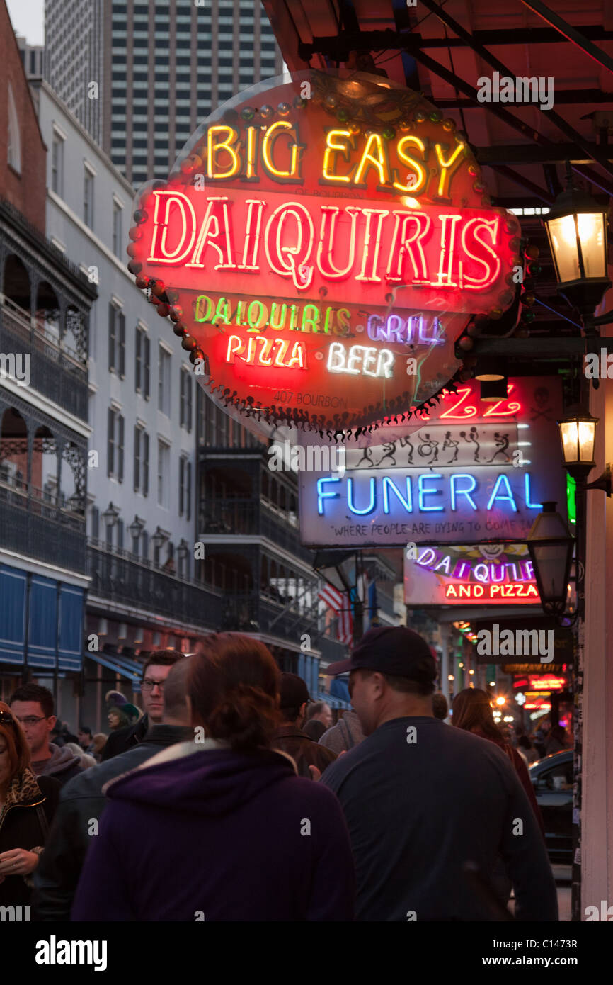 People walking below neon signs for bars and clubs along Bourbon Street ...