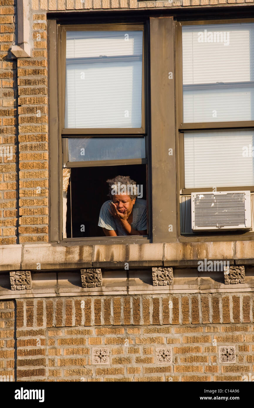African American Woman looking out apartment window in New York City ...