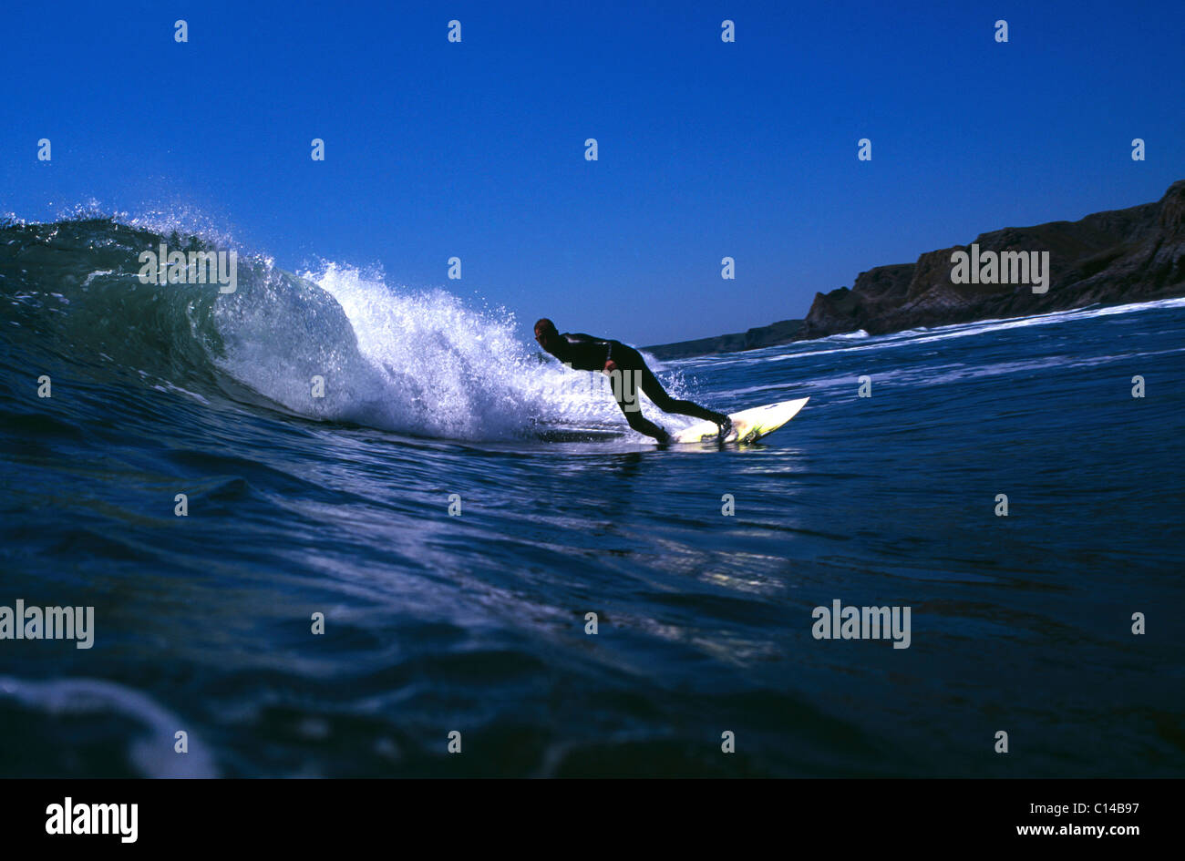 Surfer racing breaking wave on Gower Peninsula, Wales. Surfing is a ...