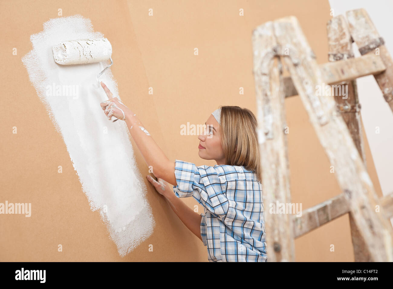 Home improvement: Woman painting wall with paint roller Stock Photo - Alamy