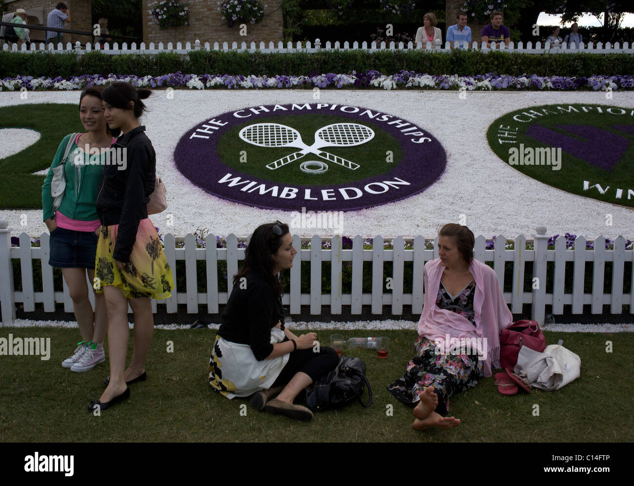 Two young ladies pose for a photograph in front of a Wimbledon design ...
