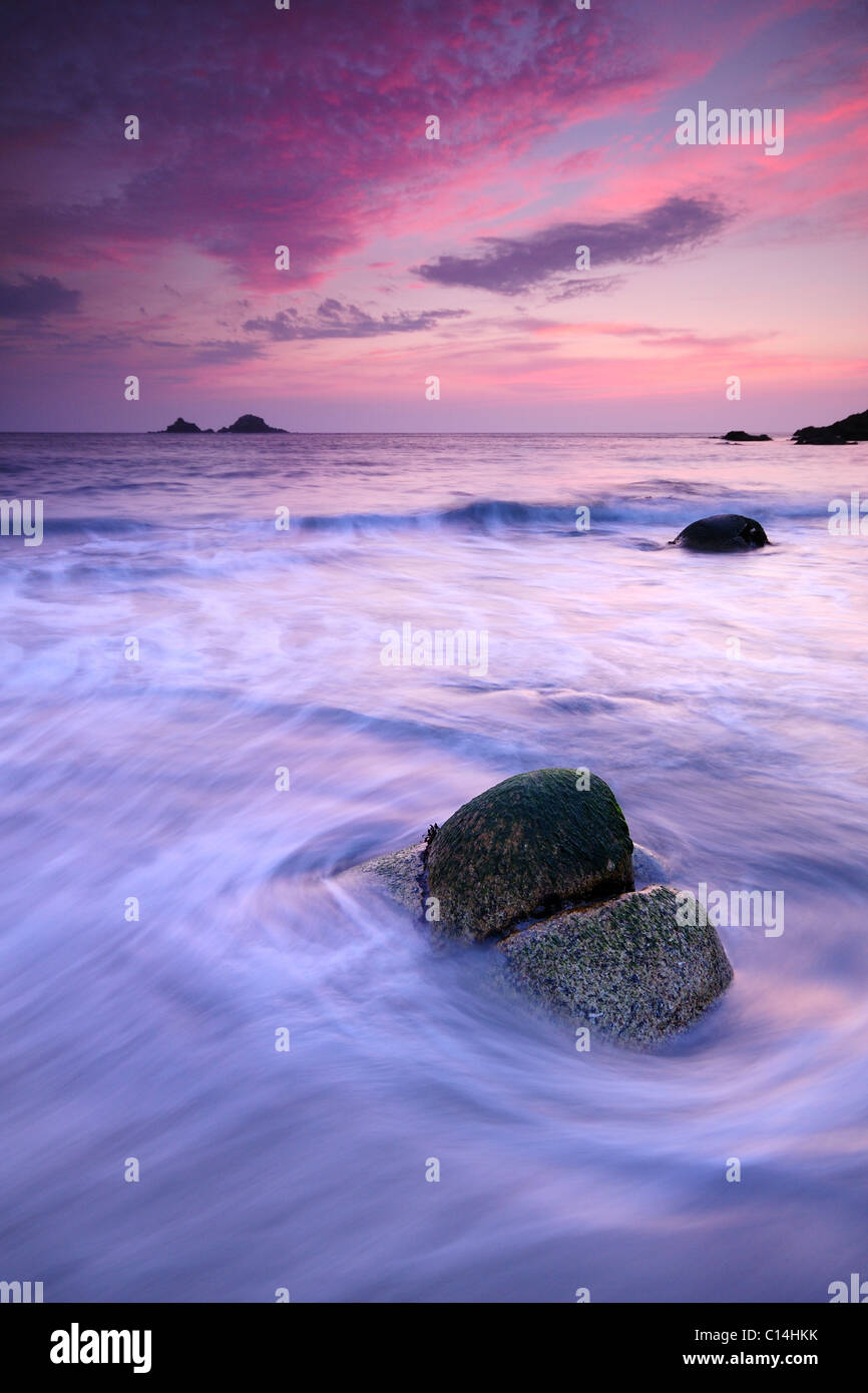 Water swirles round a small collection of rocks at Porth Nanven, during ...