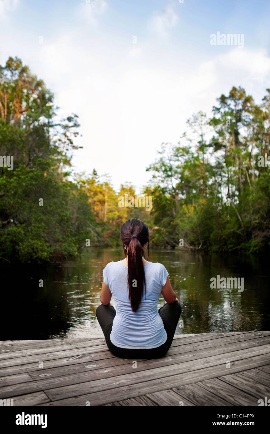 young woman relaxing on a pier looking out over a canal towards the ...