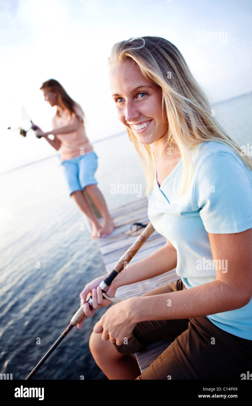 A girls smiles while fishing with her friend off a pier on the Santa ...