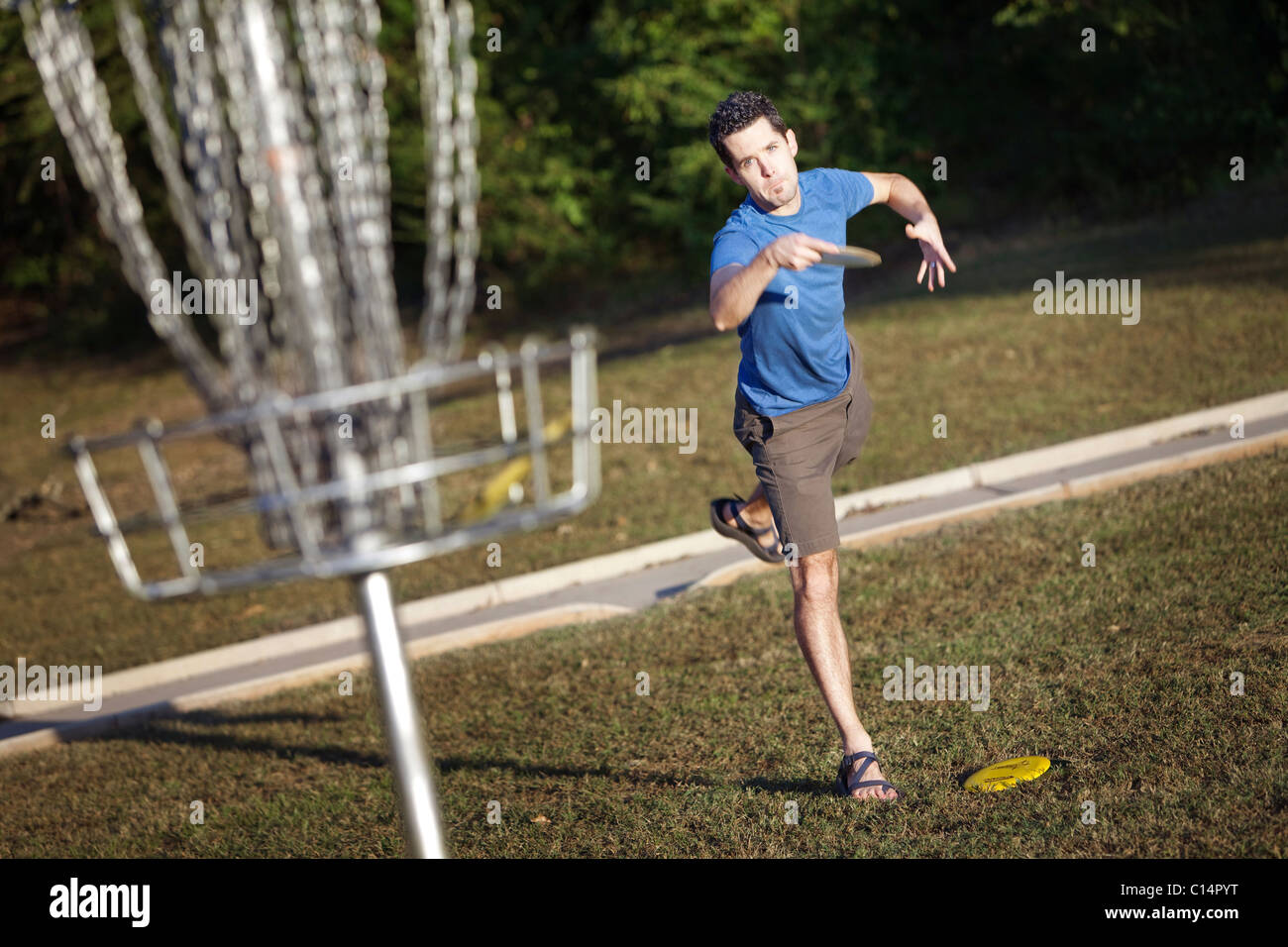 A man playing disc golf attempts a short putt Stock Photo - Alamy