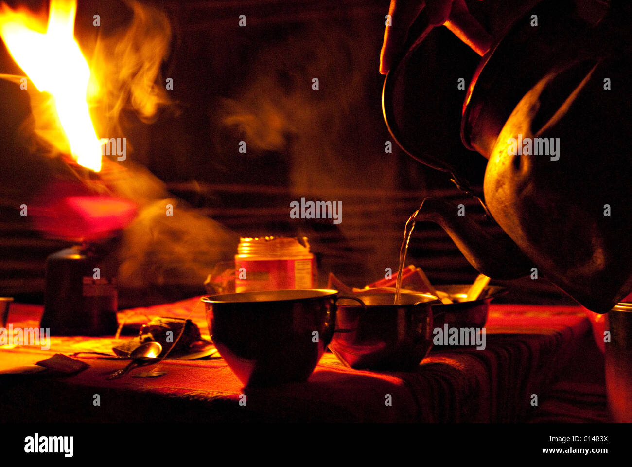 Hot water gets poured into cups, from a kettle, to make tea as a gas ...