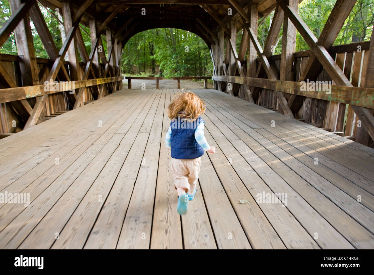 A little girl runs across a covered bridge Stock Photo - Alamy