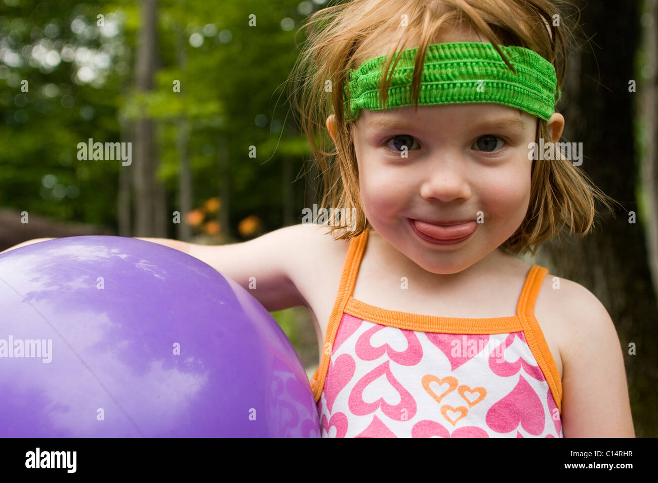 A young girl smiles while holding a purple ball Stock Photo - Alamy