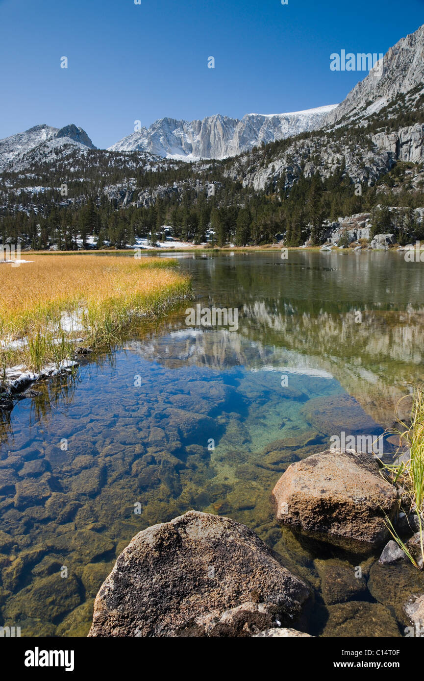 The High Sierra mountains with new fall snow reflecting in an alpine ...