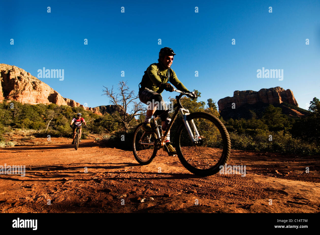 Two middle age men ride mountain bikes through the red rock country of ...