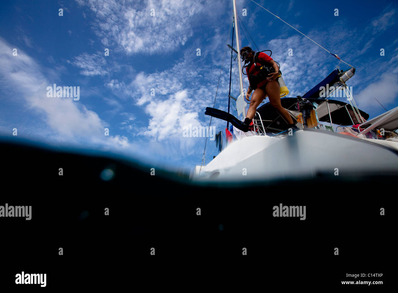 A young Hispanic woman in scuba gear jumps off a catamaran Stock Photo ...