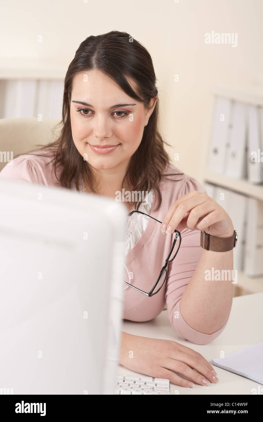 Young businesswoman watching computer screen thinking and holding ...