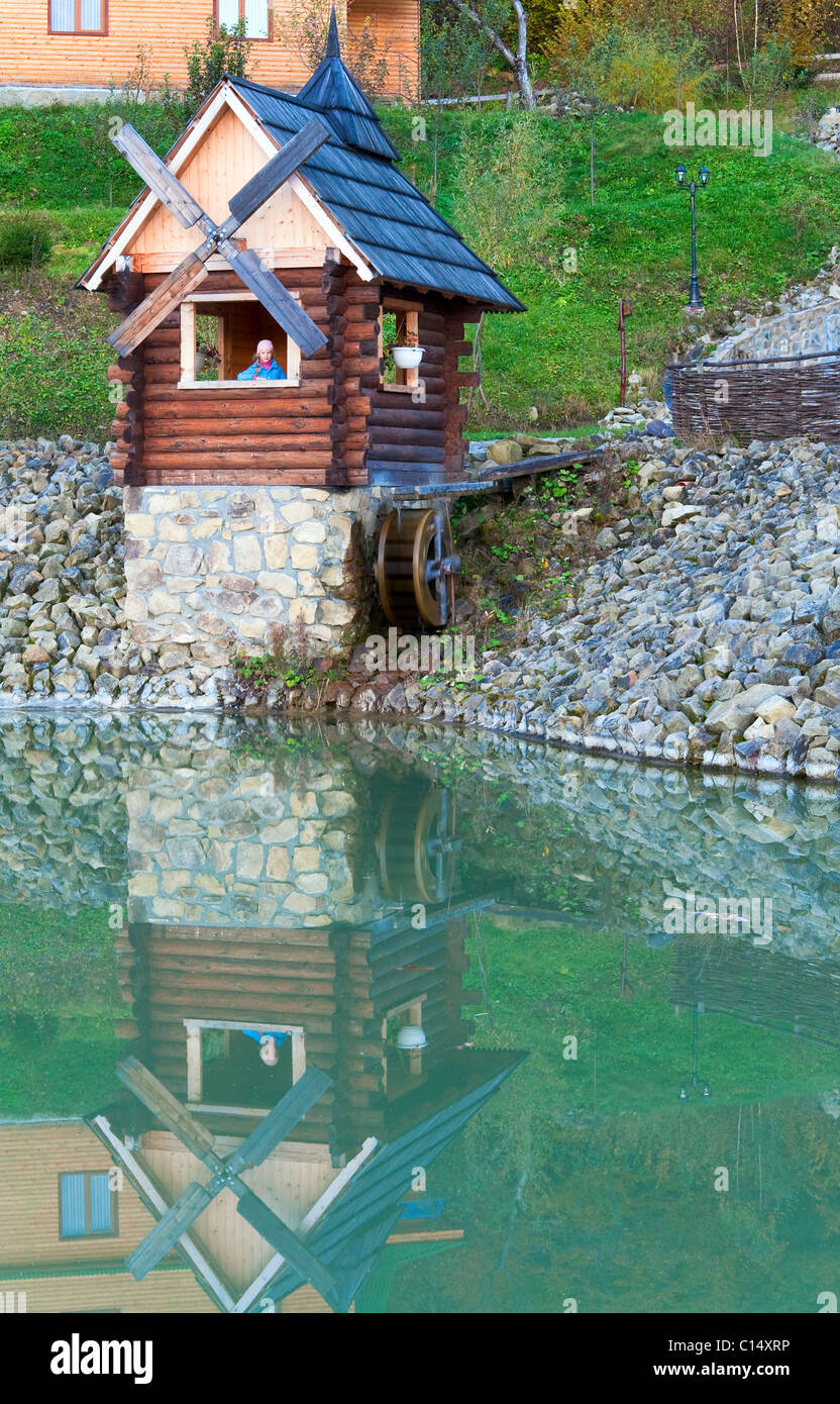 Girl in wooden house in the form of watermill near small lake Stock ...