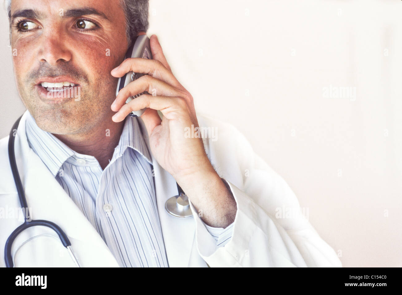 Doctor wearing lab coat with stethoscope around neck and using cell ...