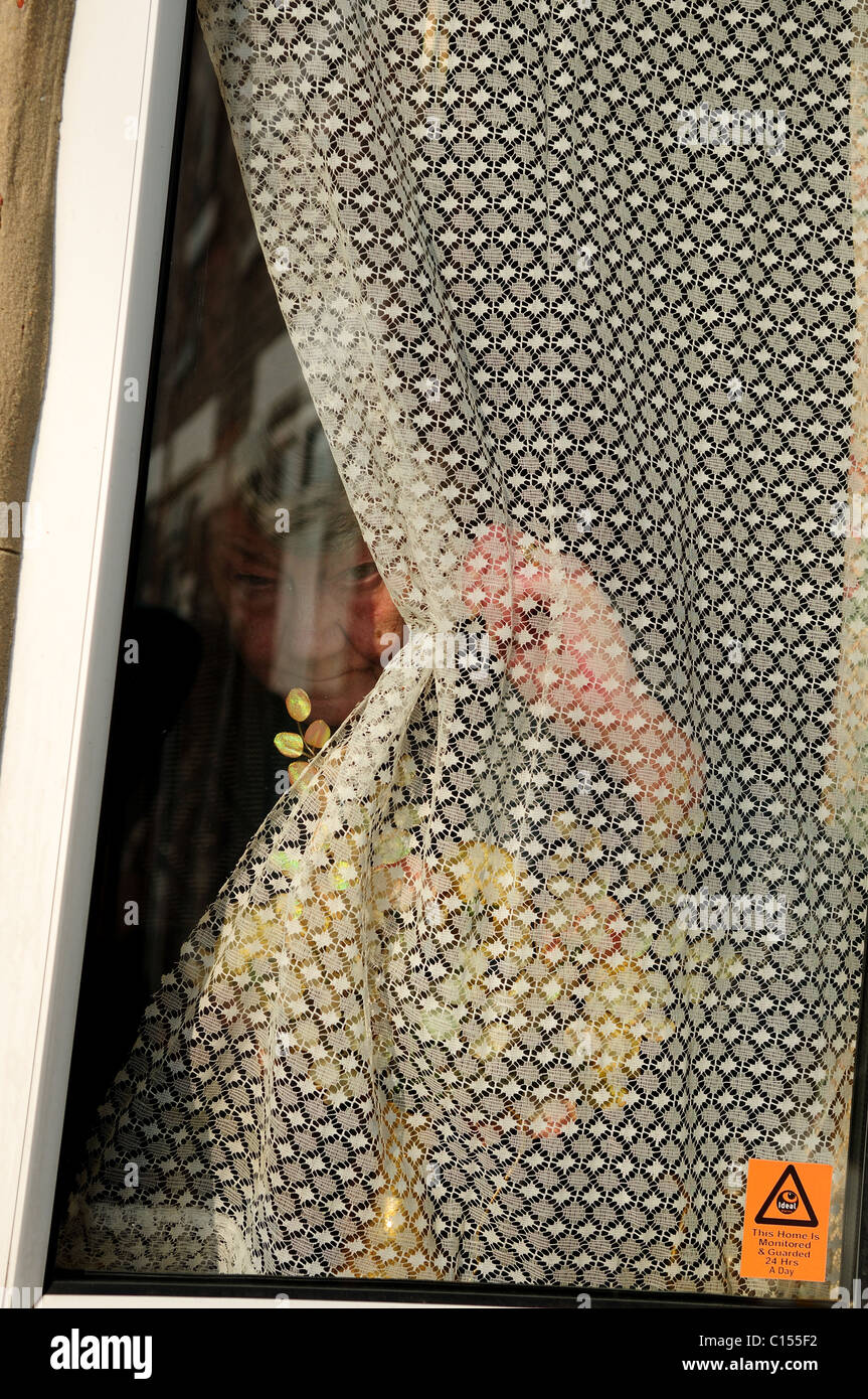 Elderly Lady Peering out of Window of Home Stock Photo - Alamy