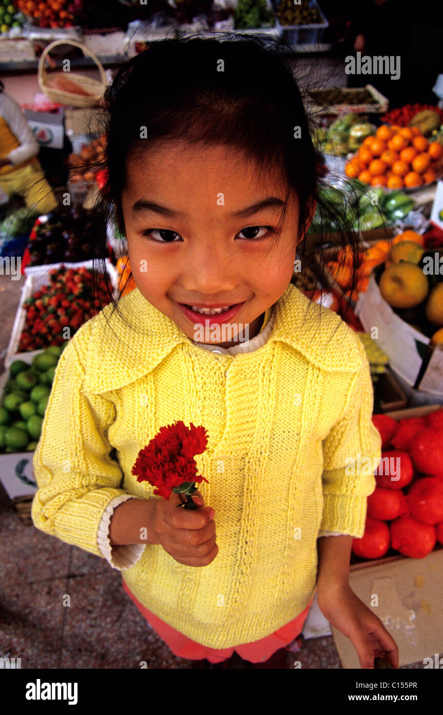 Xiamen, China. Pretty little chinese child poses with flower at public ...