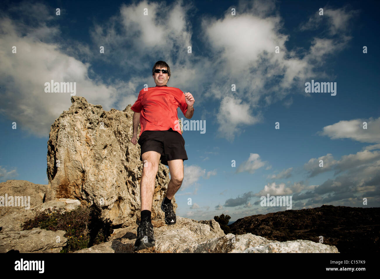 Man running across rocky terrain in the natural park of Cap de Creus ...