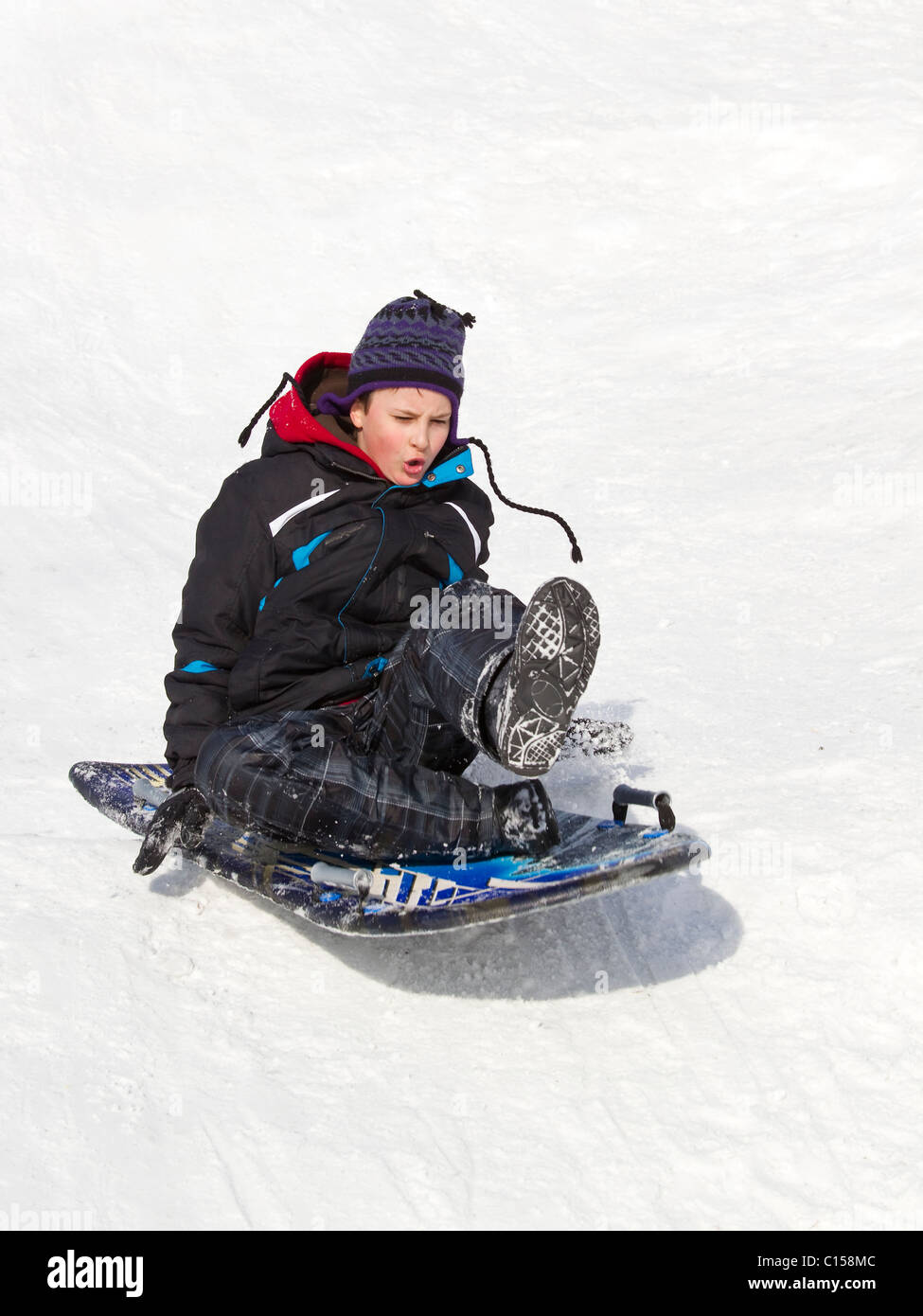 Young boy sledding down snowy hill in winter Stock Photo - Alamy