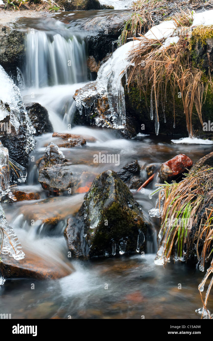 an icy stream running through rocks and grass Stock Photo - Alamy