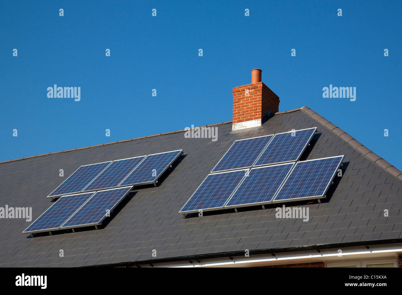 Solar or photovoltaic panels on a domestic roof with a blue sky, Kent ...