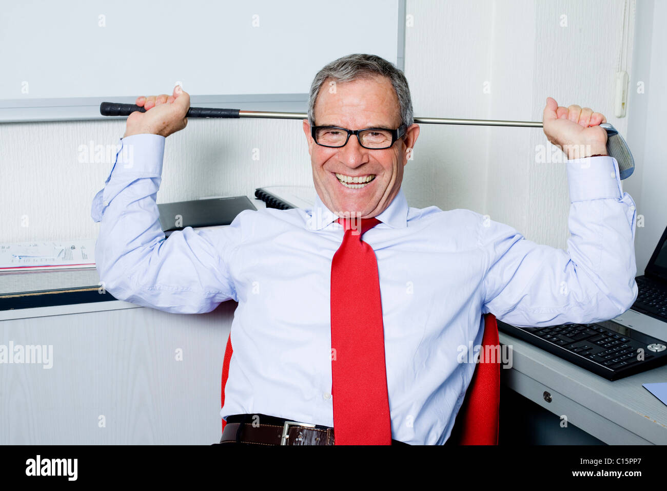 Laughing businessman holding golf club Stock Photo - Alamy
