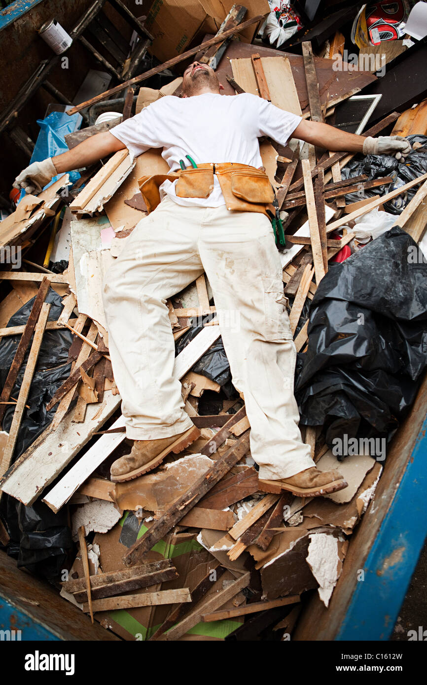 Man lying on top of pile of rubble in skip Stock Photo - Alamy
