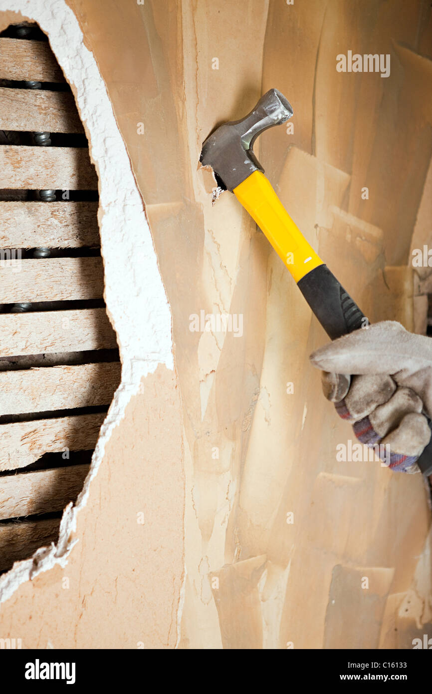 Man knocking hole in wall with hammer Stock Photo - Alamy