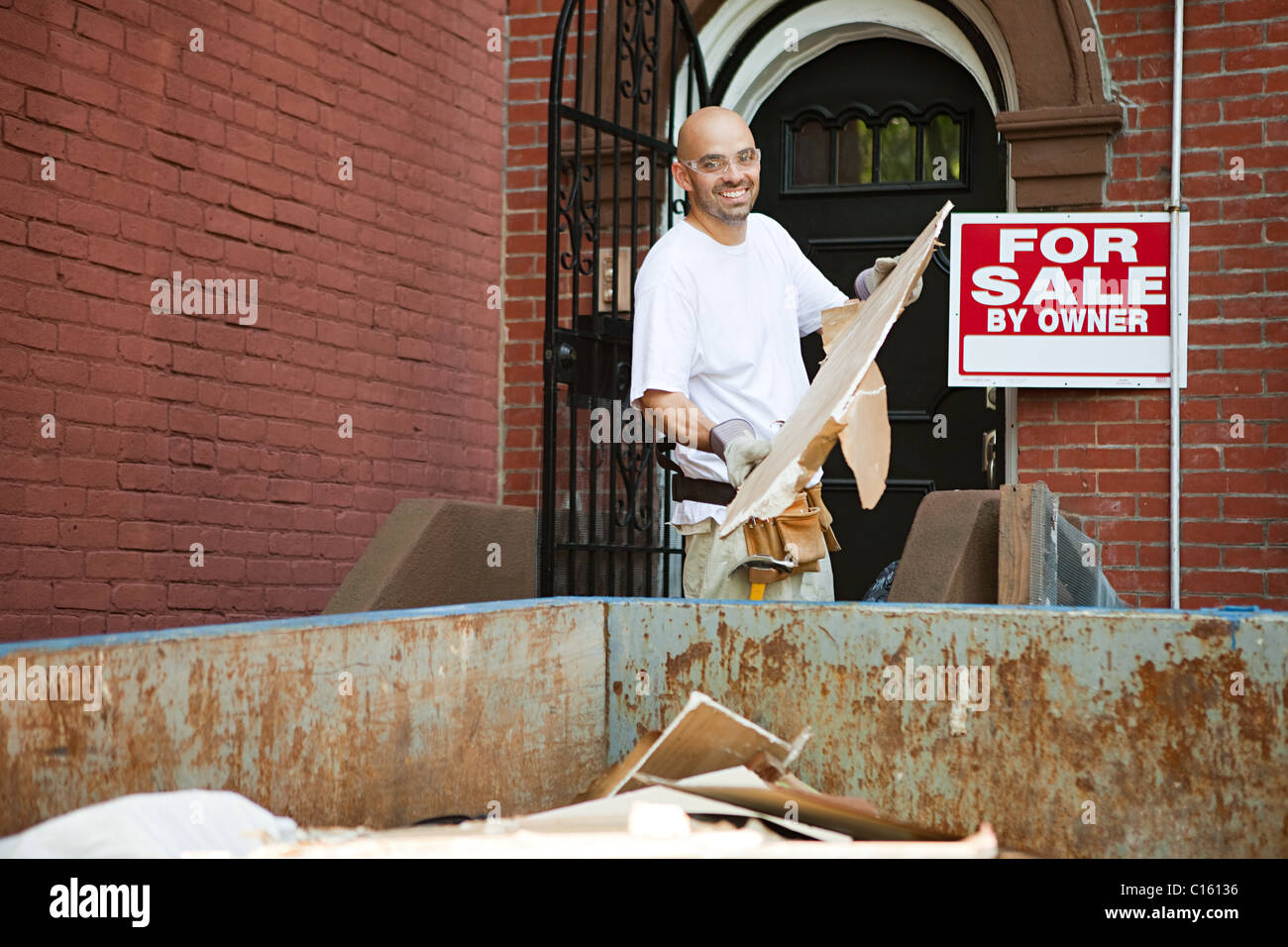 Man filling skip with rubble Stock Photo - Alamy
