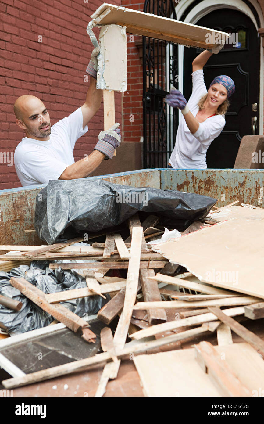 Couple filling skip with rubble Stock Photo - Alamy