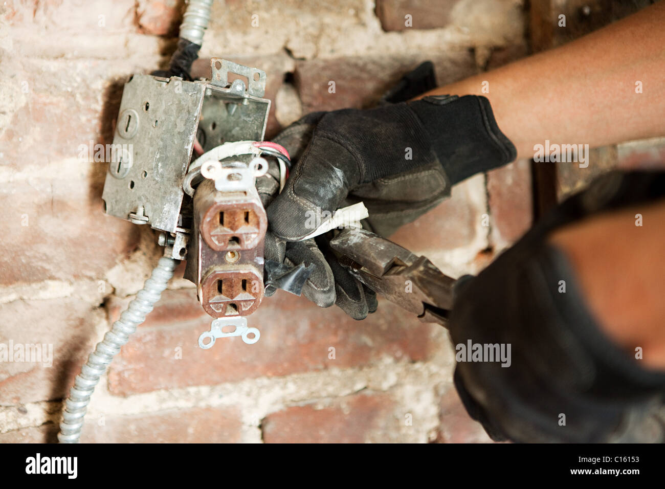 Man working on electric socket by brick wall Stock Photo - Alamy