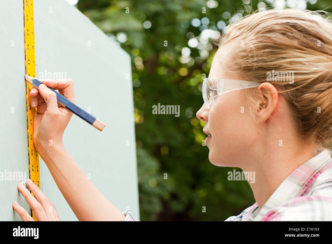 Woman measuring plywood and marking with pencil Stock Photo - Alamy