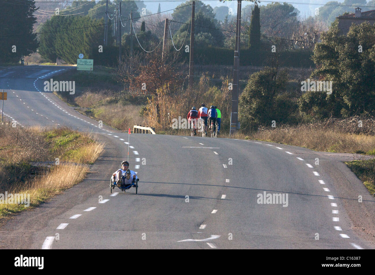 Man passing cyclists driving a trike ( three wheel bicycle) on a road ...