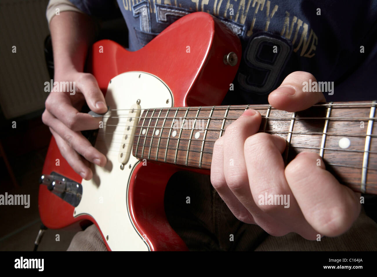 Teenage boy playing vintage red and white electric telecaster fender ...