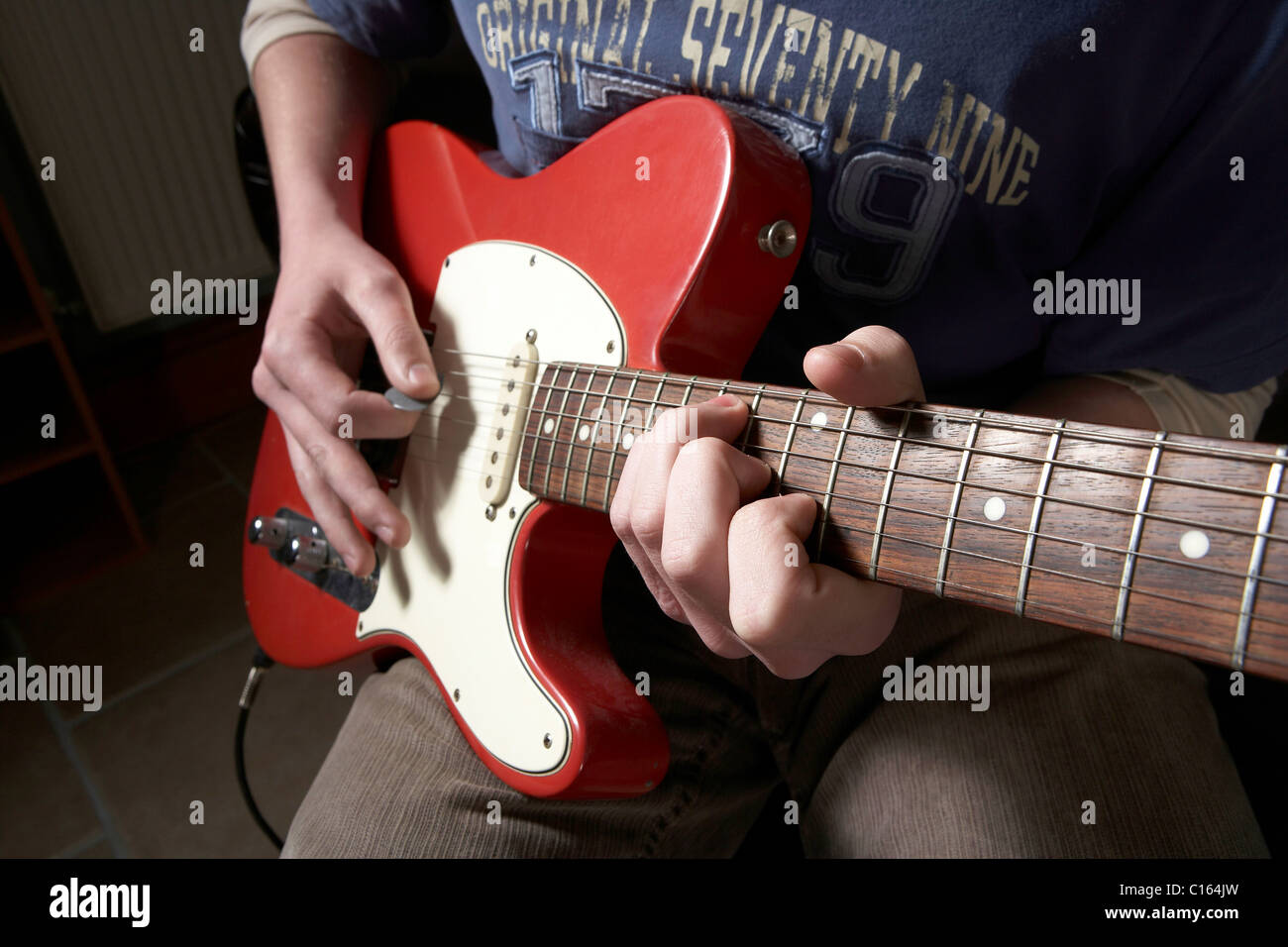 Teenage boy playing vintage red and white electric telecaster fender ...