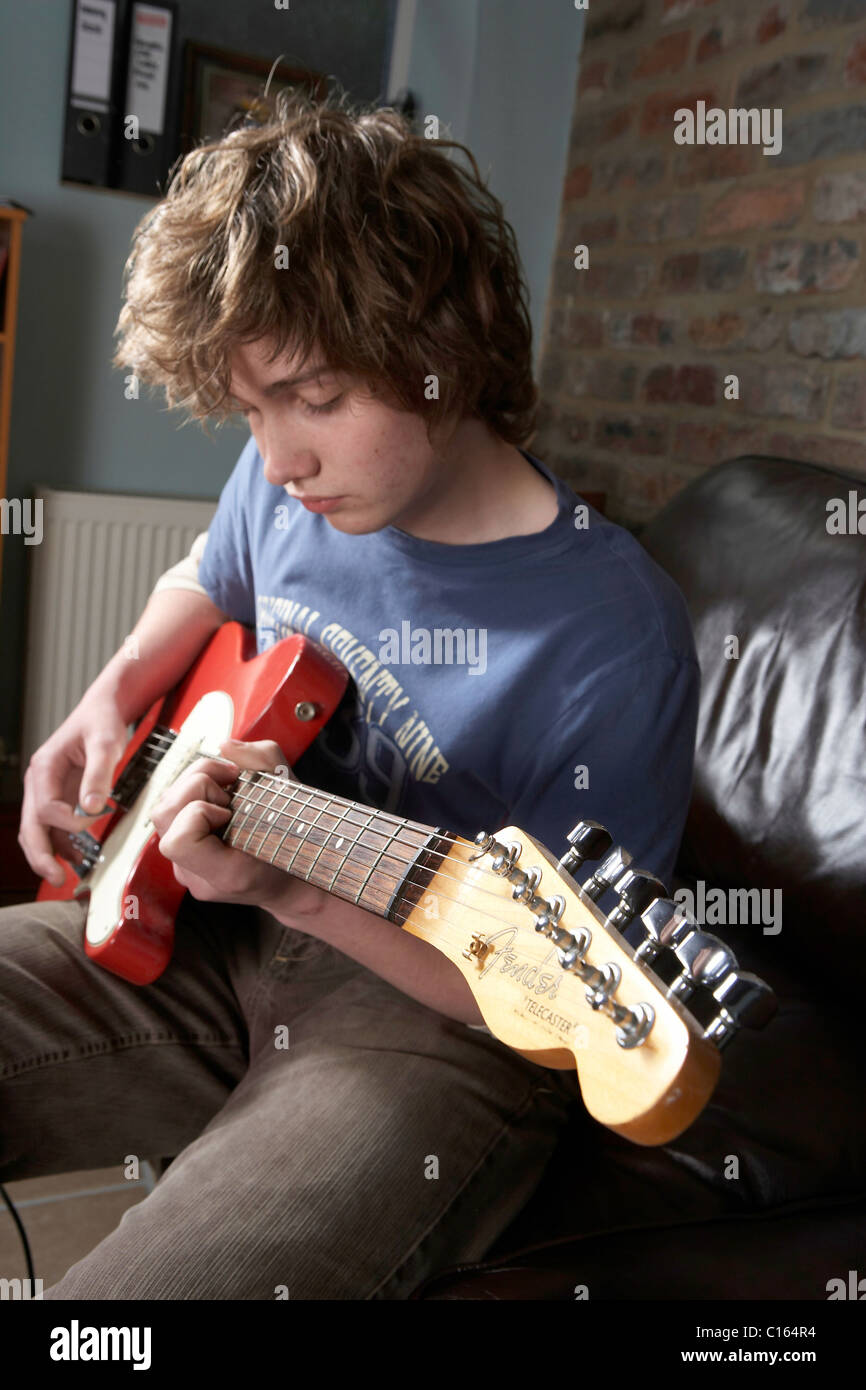 Teenage boy playing vintage red and white electric telecaster fender ...