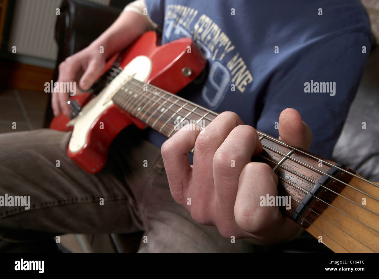 Teenage boy playing vintage red and white electric telecaster fender ...