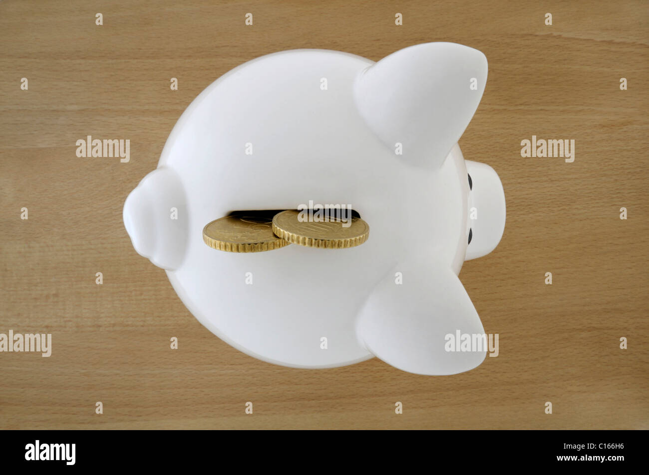 White piggy bank with two-Euro coins, gold coloured, in the slot, on a ...
