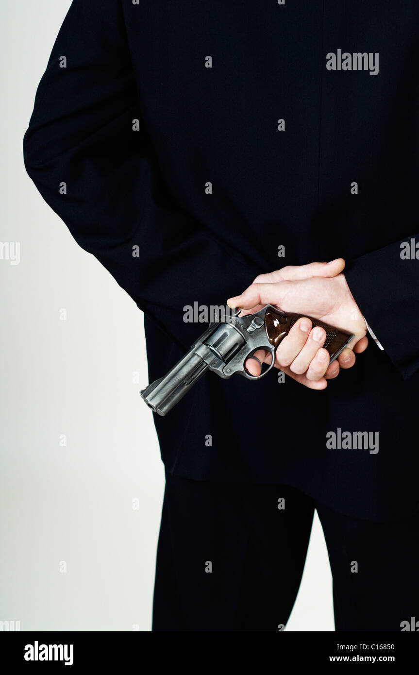 Man hiding a revolver behind his back Stock Photo - Alamy