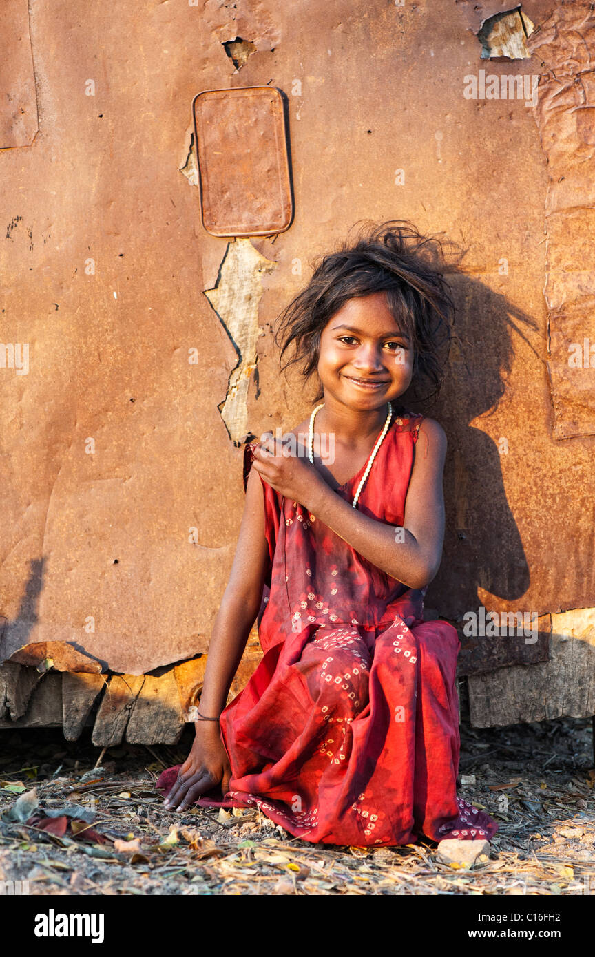 Happy young poor lower caste Indian street girl smiling sat against a ...
