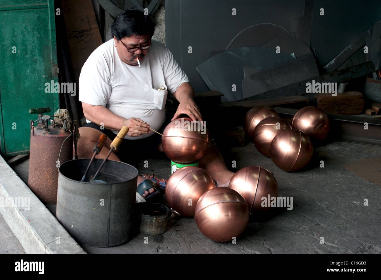 A large Chinese man smoking and wearing glasses is working in a ...