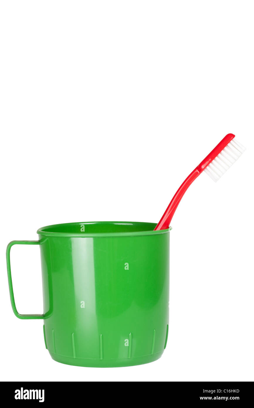 Green plastic mug with red toothbrush isolated on white background ...