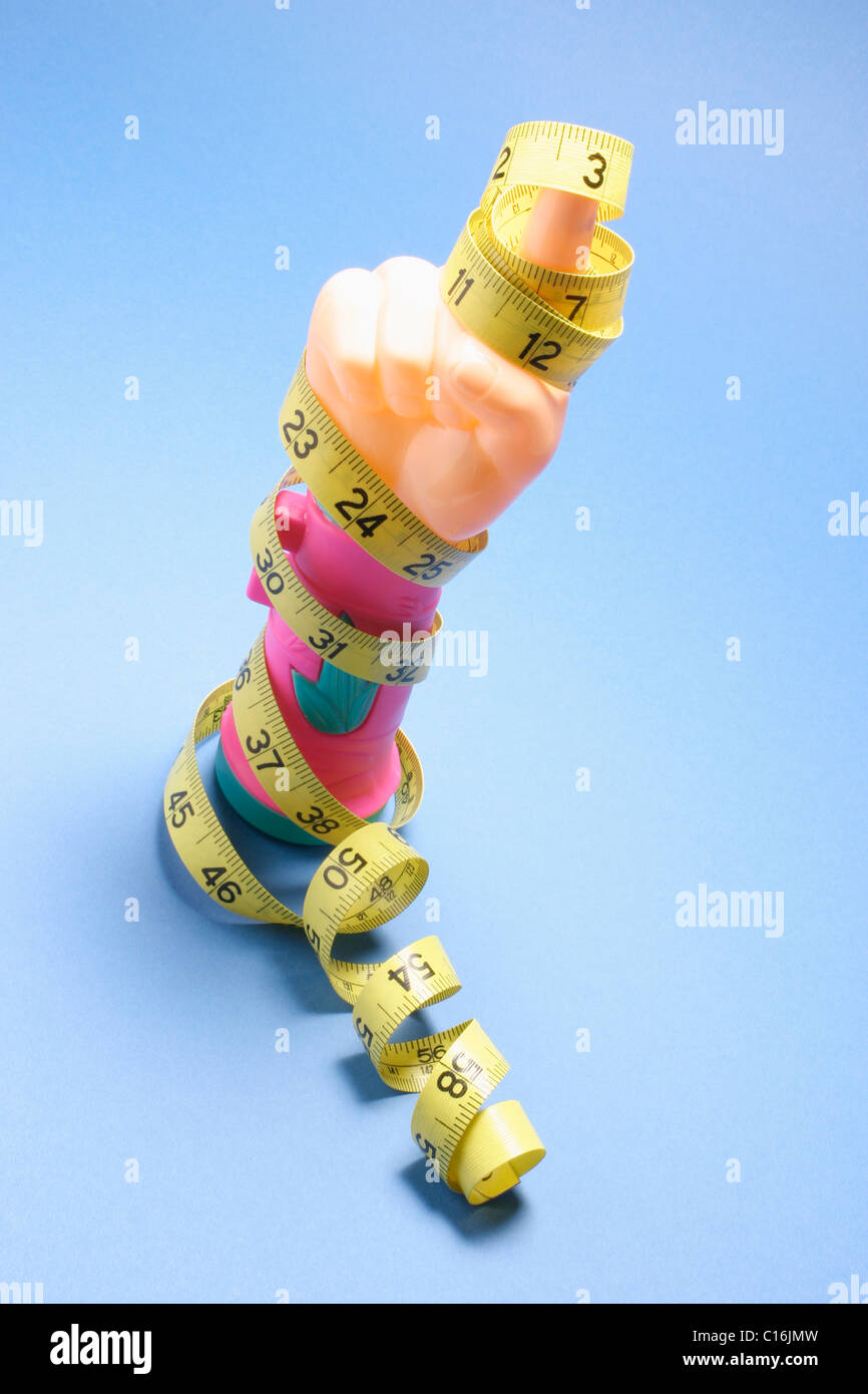 Tape measure around plastic toy hand Stock Photo - Alamy