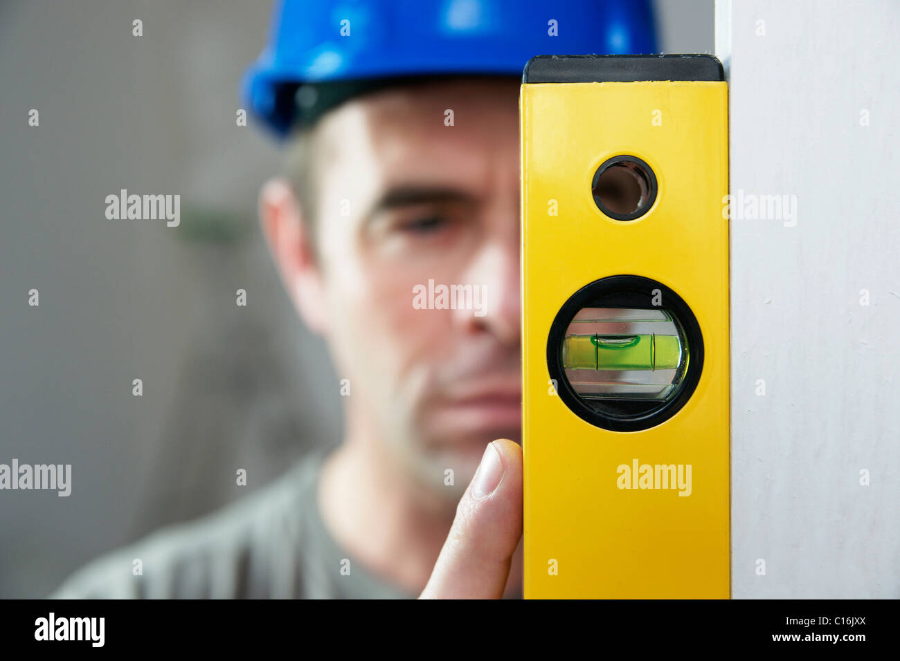 Workman wearing a hard helmet, using a water level Stock Photo - Alamy