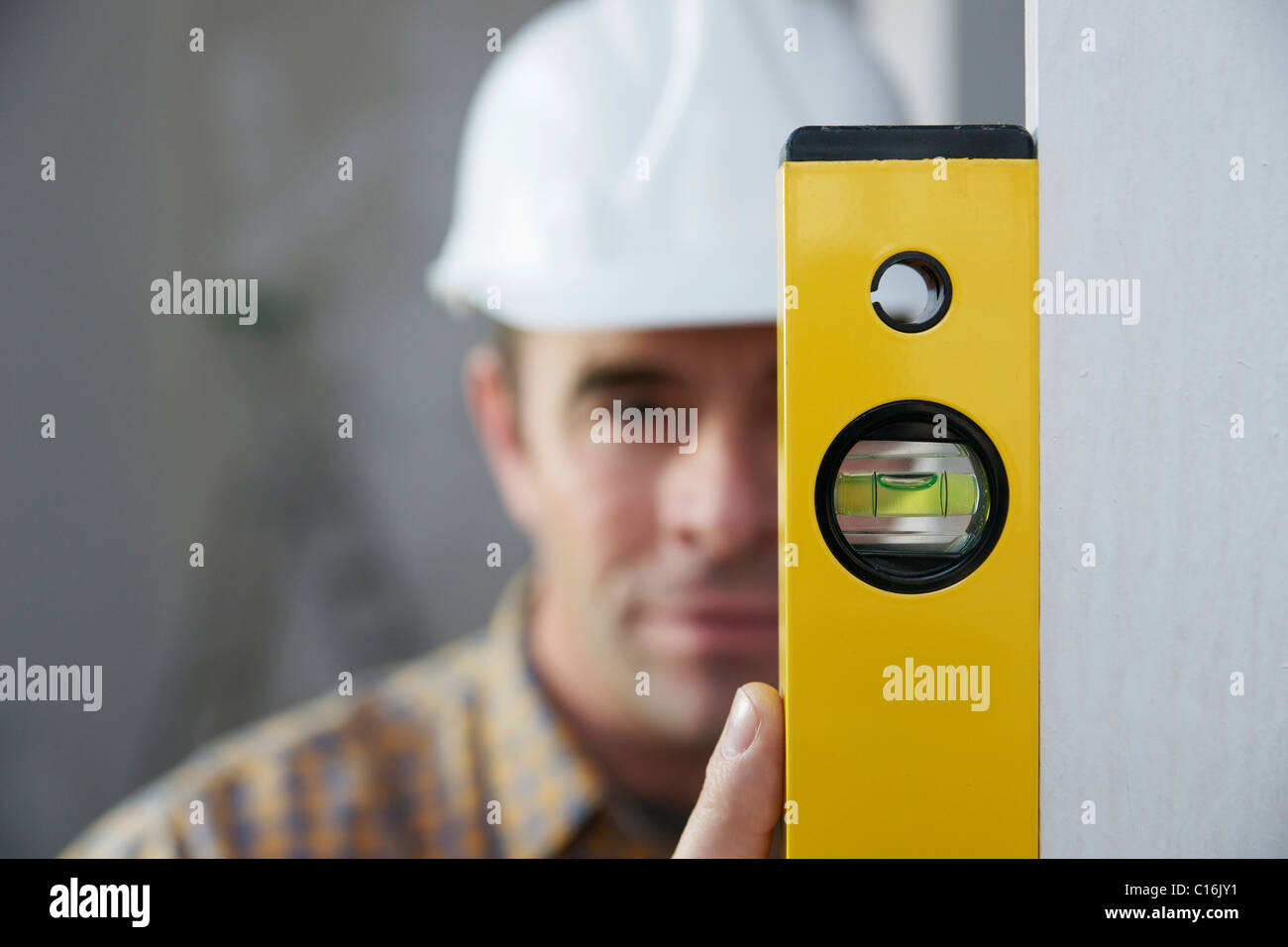 Workman wearing a hard helmet, using a water level Stock Photo - Alamy