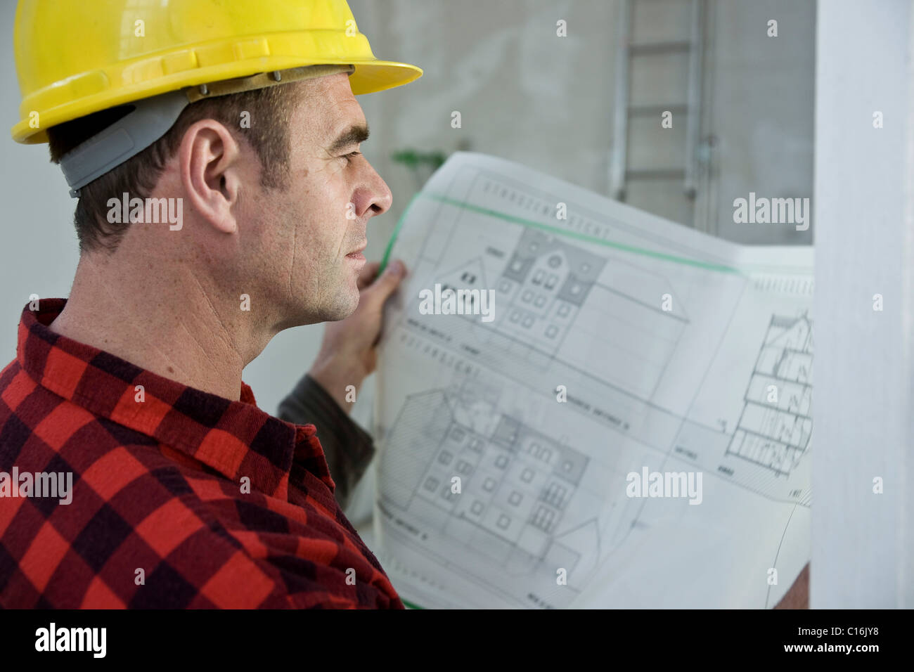 Workman wearing a hard helmet, looking at a construction plan Stock ...