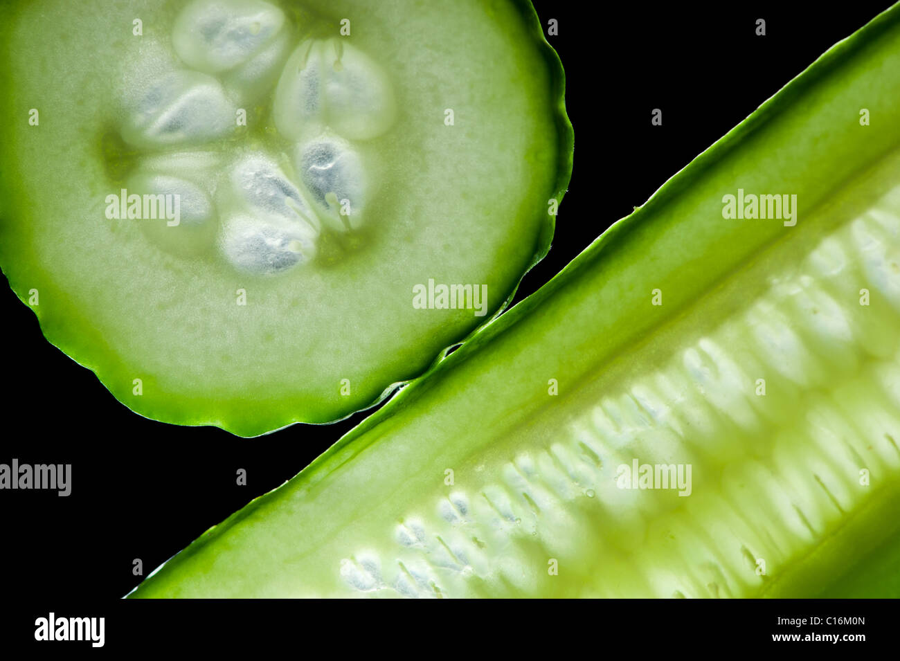 Macro of slim sliced cucumber isolated on black background Stock Photo ...
